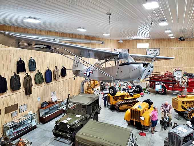 A light aircraft hangs suspended from the ceiling, while vintage vehicles below create a three-dimensional timeline of transportation evolution.