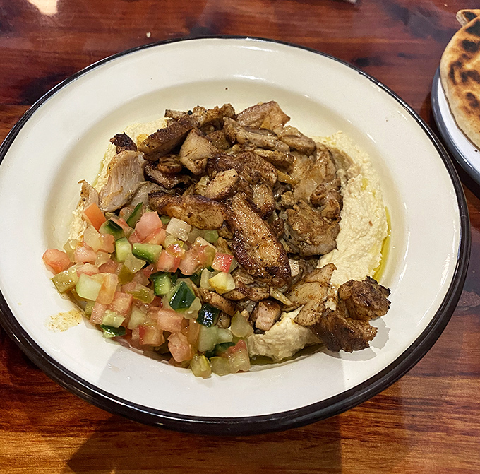 Silky, cloud-like hummus crowned with perfectly seasoned chicken and bright vegetables &ndash; proof that simplicity, when done right, creates culinary magic.