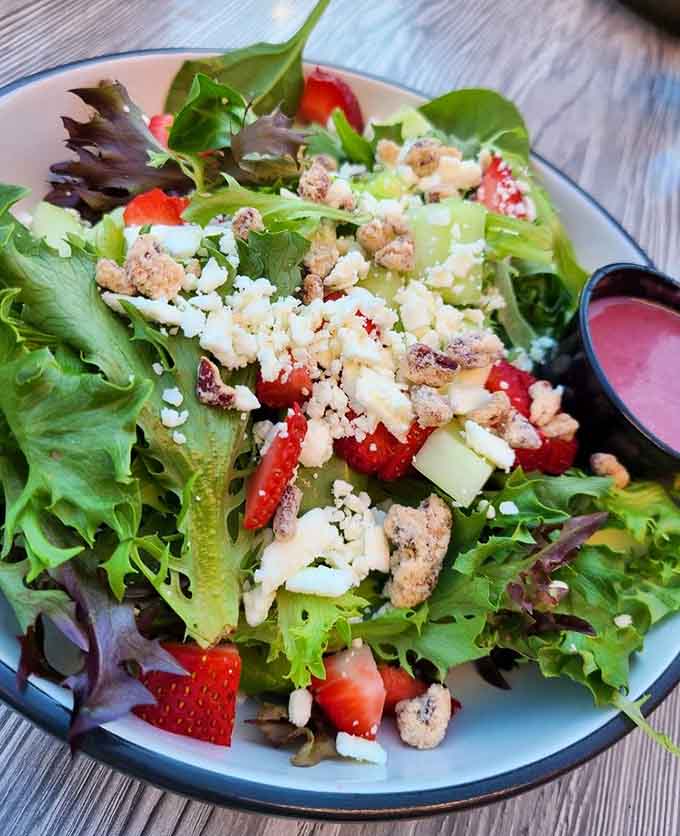 Fresh greens, vibrant strawberries, and crumbled cheese create a colorful composition that proves healthy eating doesn't have to be boring or sad.