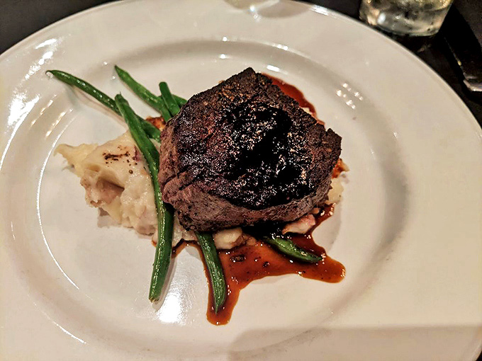 The filet mignon sits regally atop mashed potatoes with green beans &ndash; a composition as visually satisfying as it is delicious.
