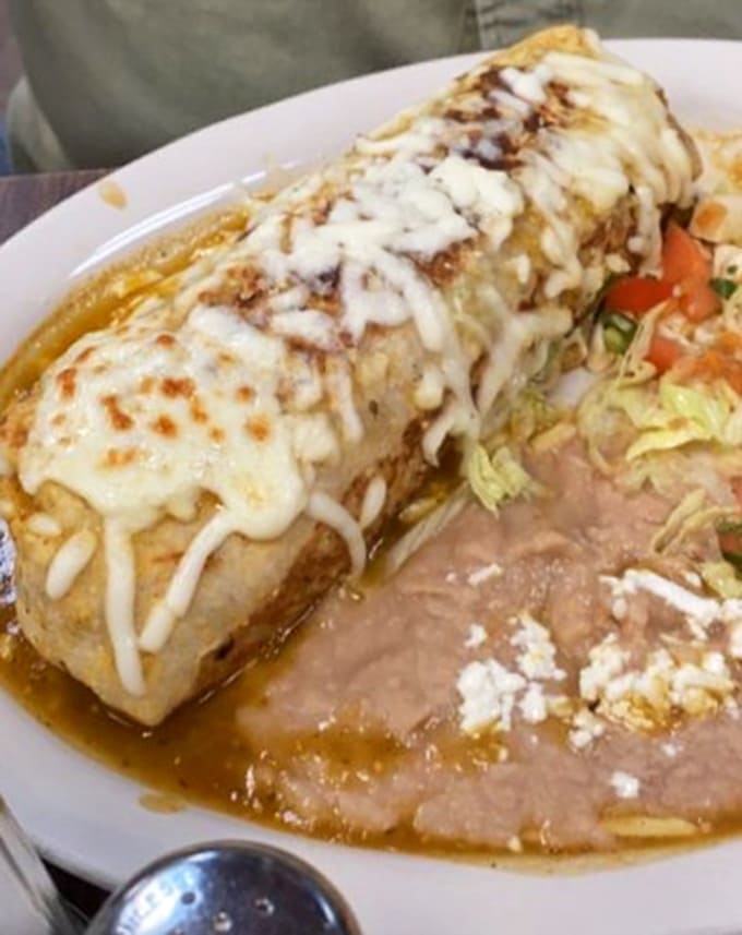 That green salsa blanket and melted cheese crown transform this burrito into edible art, proving beauty and deliciousness aren't mutually exclusive.