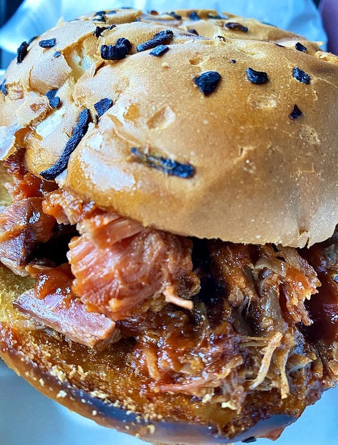 The BBQ beef brisket sandwich piles smoky meat high on a sesame seed bun, creating a handheld masterpiece that requires multiple napkins.