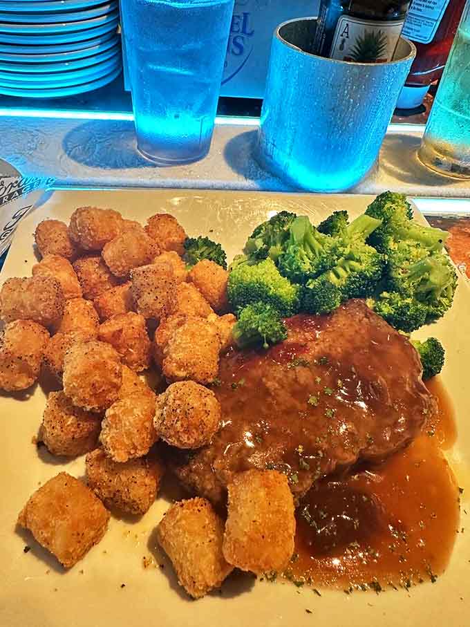 Comfort food gets the premium treatment with this meatloaf bathed in savory gravy, flanked by crispy tots and vibrant broccoli.