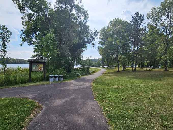 This peaceful lakeside trail invites easy strolls where sunlight filters through trees and the water sparkles nearby.