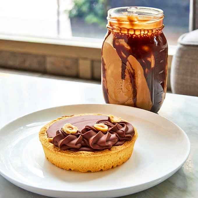 The Nutella tart sits regally on its white throne, chocolate ganache gleaming like it's auditioning for a dessert magazine cover.