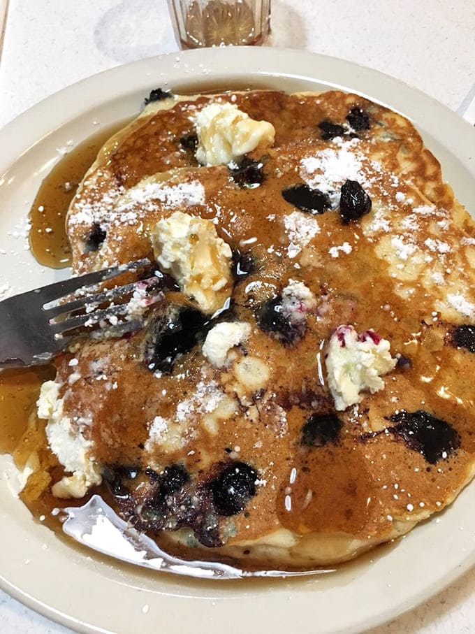 Pancakes that defy gravity: These fluffy discs of joy come studded with blueberries that burst with each bite, creating tiny flavor explosions.