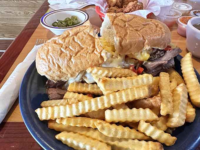 The Philly Beef sandwich arrives loaded with tender meat and melted cheese, accompanied by perfectly crispy crinkle-cut fries.