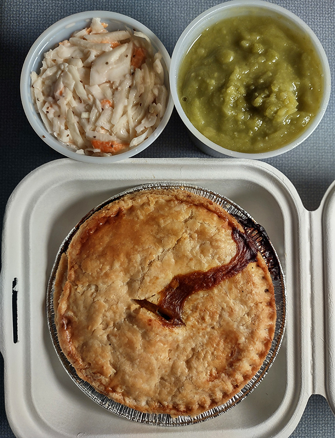 Mushy peas accompany a traditional meat pie, its golden crust hiding savory treasures within &ndash; British comfort food at its finest.