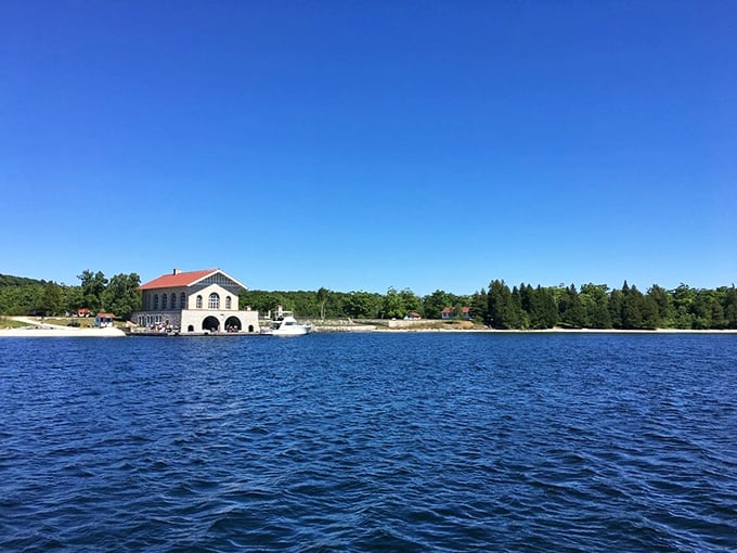The historic waterfront building stands sentinel over blue waters, a reminder of simpler times when everything moved at the pace of waves.