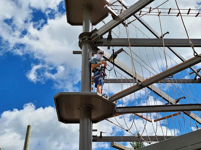 Perched on a platform high above the ground, participants prepare for their next aerial challenge with determination.
