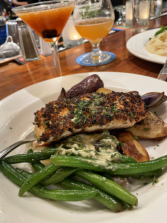 This herb-crusted salmon rests atop vibrant green beans – proof that simple ingredients become extraordinary in the right hands.