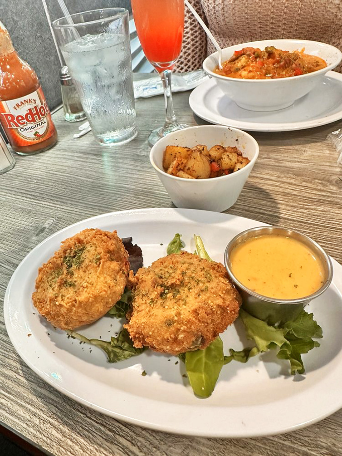 Golden-brown salmon croquettes perched on fresh greens with dijon sauce &ndash; crispy exterior giving way to flaky salmon that practically melts on your tongue.