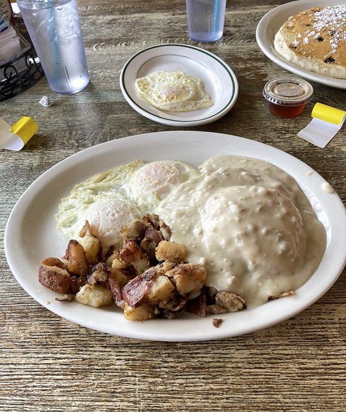 Biscuits swimming in creamy sausage gravy with perfectly cooked eggs and home fries. A plate that says "Go back to bed? Not today!"