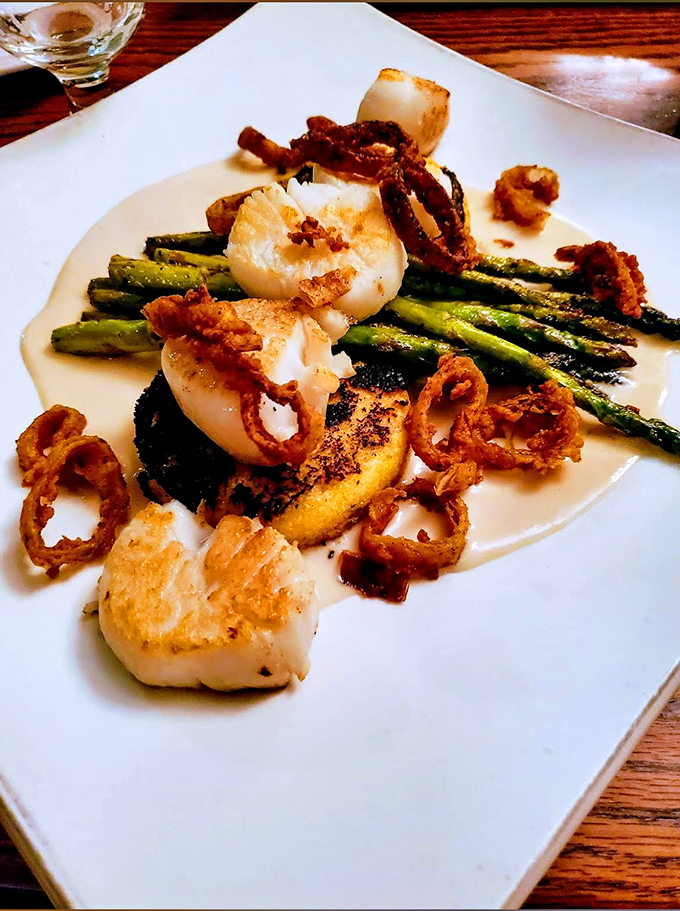 Perfectly seared scallops dance with crispy asparagus and fried onions &ndash; proof that pub food can rival fine dining without the pretense.