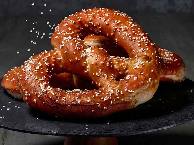 Treat yourself to these golden, oven-baked soft pretzels, featuring a perfect dusting of coarse salt for your next delicious snack.