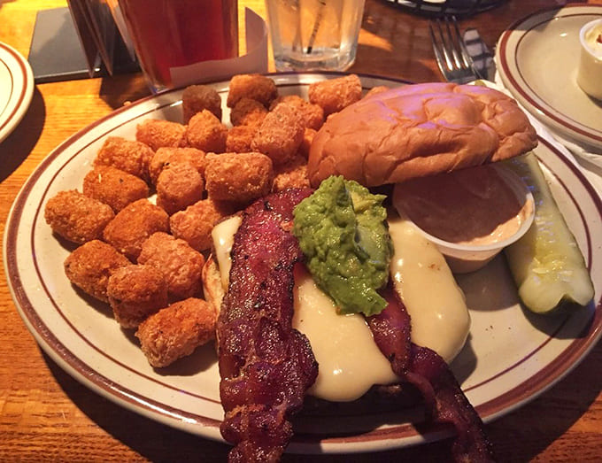 Golden tater tots and a loaded burger create a plate of pure happiness that requires strategic eating and zero regrets.