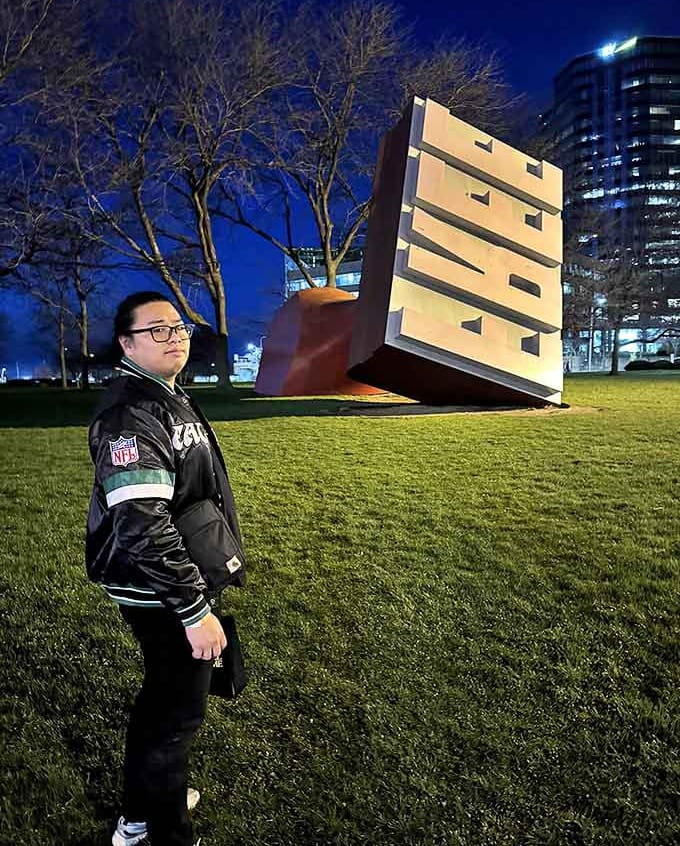 A visitor contemplates the oversized sculpture at night, when fewer crowds allow for quiet reflection on this monument to creative freedom.