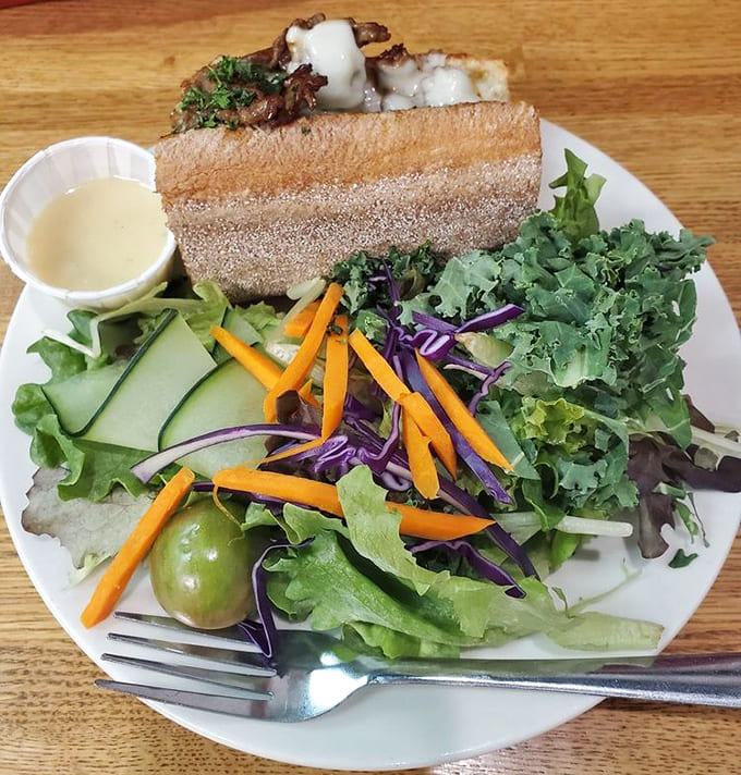 The half steak sandwich paired with a vibrant salad proves you can have your vegetables and your perfectly cooked beef too, living that balanced life one bite at a time.