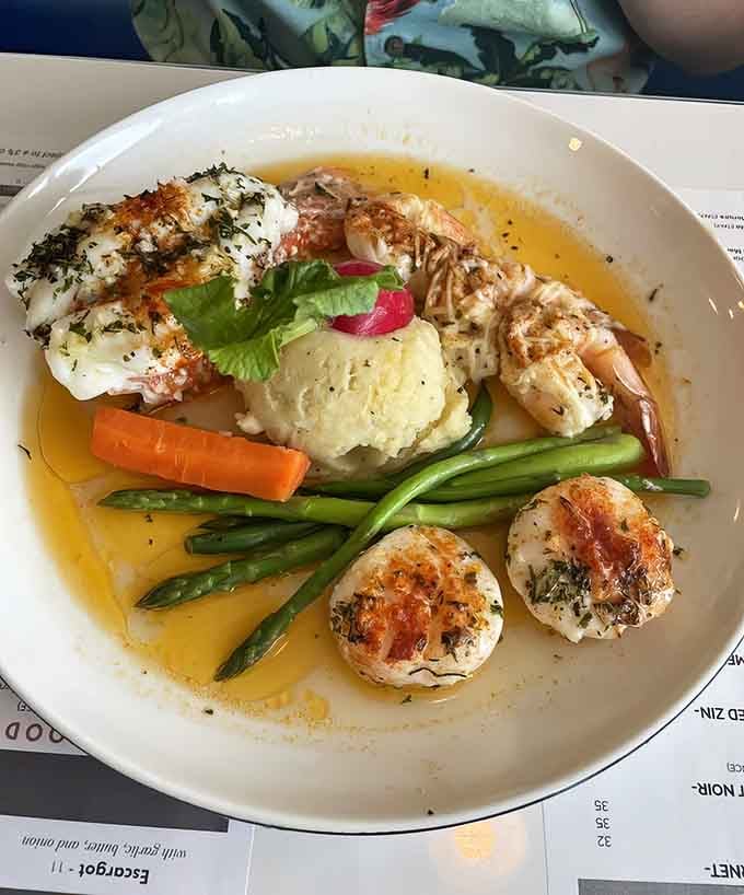 Fresh seafood gets the royal treatment with shrimp, scallops, and fish swimming in golden butter sauce alongside crisp vegetables.