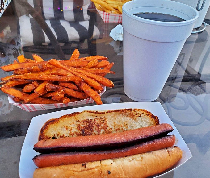 A classic hot dog nestled in a toasted bun keeps company with those famous sweet potato fries and an ice-cold soda.