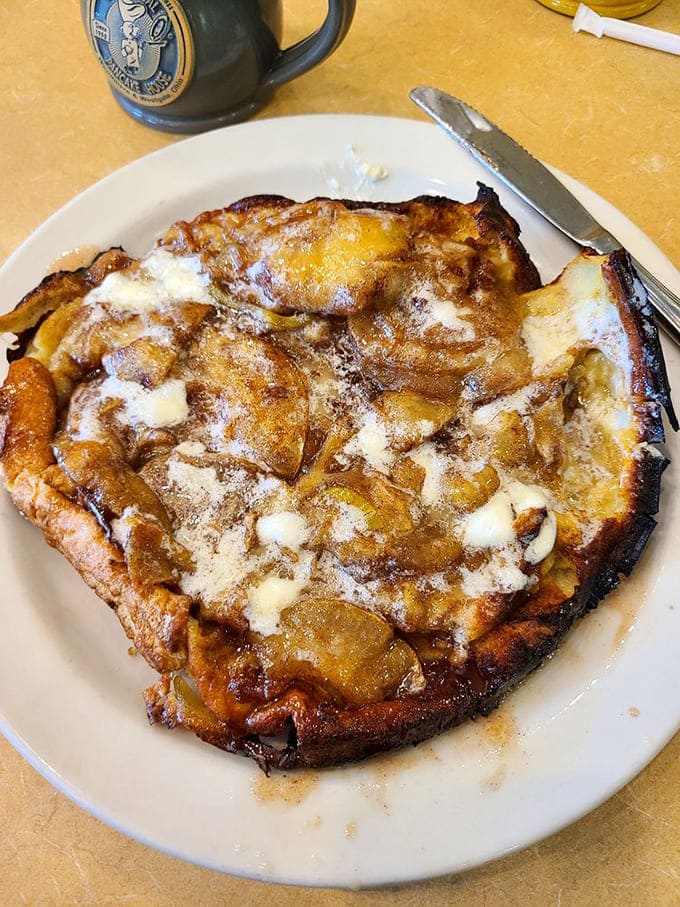 The baked apple pancake arrives looking like something from a fairy tale, caramelized and crowned with butter.