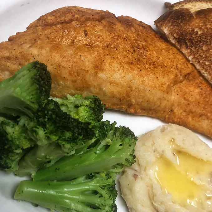 Pan-fried walleye arrives golden and flaky alongside bright green broccoli, proving simple preparations often yield the best results.