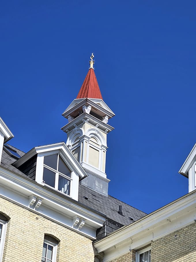 The distinctive red spire reaches skyward, a Victorian architectural flourish that makes the building instantly recognizable against Michigan's blue skies.