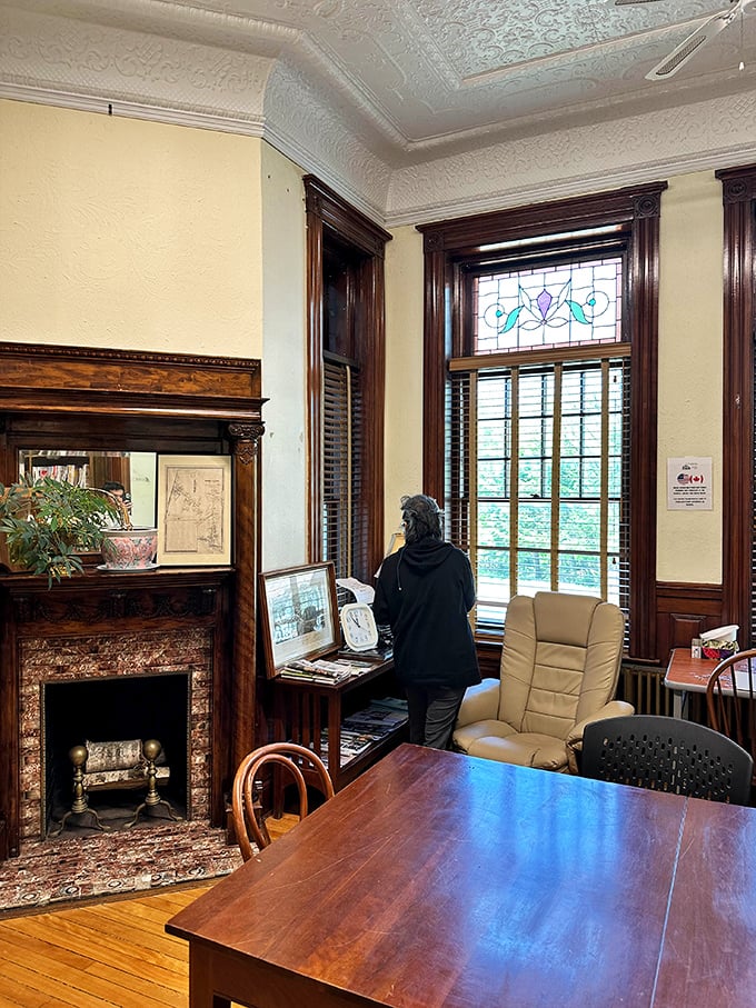 History comes alive as a visitor explores artifacts near the original fireplace, where warmth has welcomed readers from two nations for over a century.