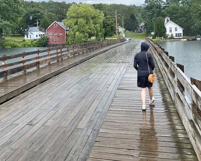 Rain-slicked planks glisten as a solitary figure crosses the Floating Bridge, each step creating gentle ripples in the lake below.