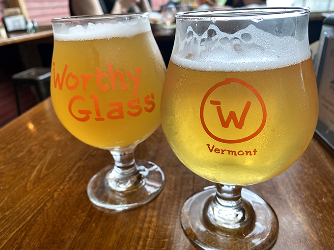 Two Worthy Glasses filled with Vermont craft beer catch the light, their contents promising the perfect complement to the restaurant's wood-fired creations.