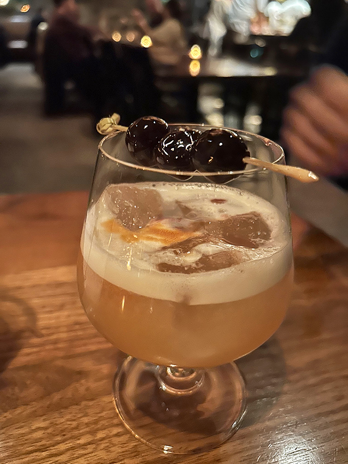 Cocktails at Hen of the Wood aren't just drinks, they're liquid storytelling &ndash; this one garnished with plump cherries that hint at the complex flavors within.