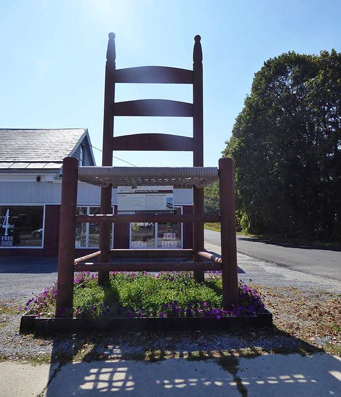 Bathed in sunshine, the chair's warm wooden tones glow against lush greenery. Vermont summers give this giant its best lighting.