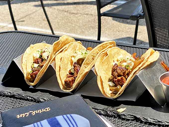 Three perfectly crafted tacos stand at attention, their simple presentation belying the complex flavors within &ndash; proof that fusion cuisine works best when it doesn't try too hard.