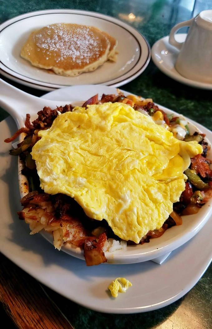 A study in breakfast contrasts: spicy, savory chorizo skillet alongside a sweet, fluffy pancake dusted with powdered sugar.