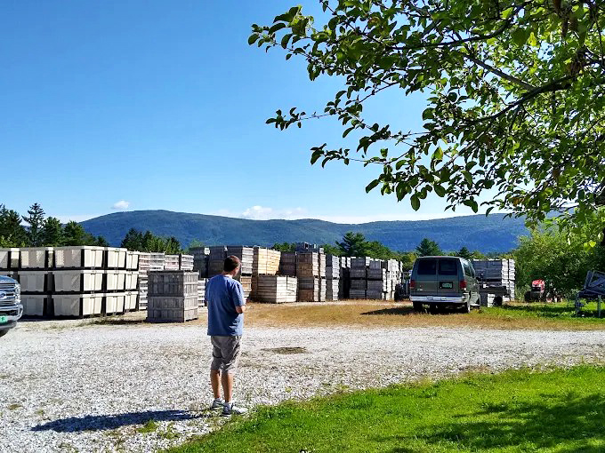 Wooden apple crates stacked against the mountain backdrop remind visitors that farming and landscape are inseparably woven in Vermont's identity.