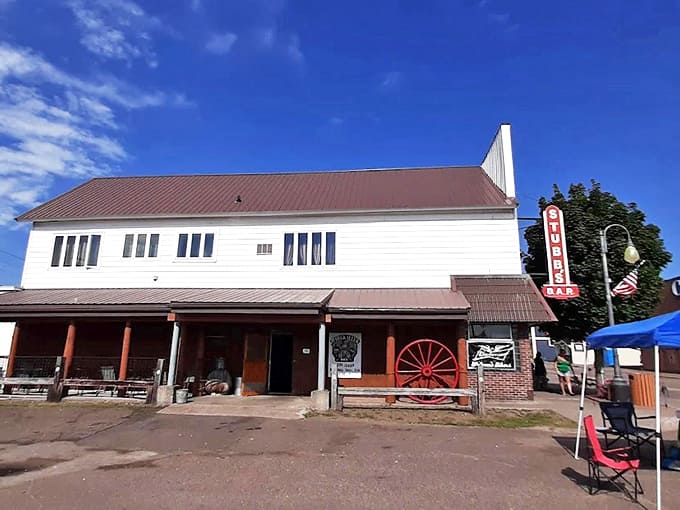 Stubbs Bar's rustic white exterior and vintage wagon wheel hint at the historical treasures waiting inside this unique Upper Peninsula museum-tavern.