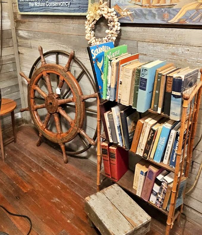 A ship's wheel stands sentinel beside carefully curated maritime volumes &ndash; Hemingway would approve of this literary corner's salty character.
