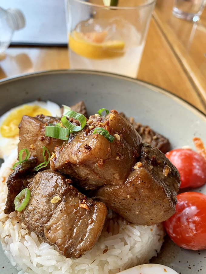 Tender chunks of adobo-seasoned meat rest atop fluffy rice&mdash;comfort food elevated through careful preparation and bold seasoning.