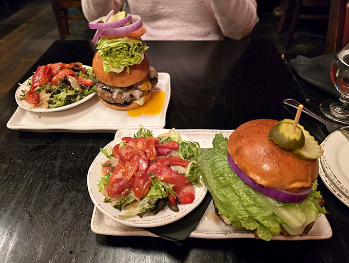These burgers tower so high, they might need their own building permit. The side salad's just for show.