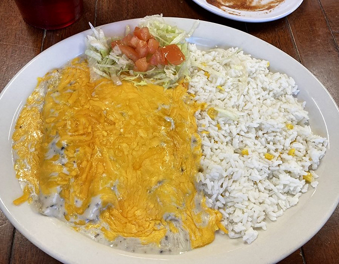 Chicken enchiladas bathed in creamy mushroom sauce sit beside rice studded with corn &ndash; a delicious departure from traditional red sauce versions.