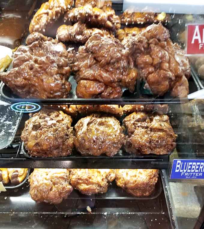 Apple fritters and blueberry fritters stacked high, proving that fried dough is always the right answer.