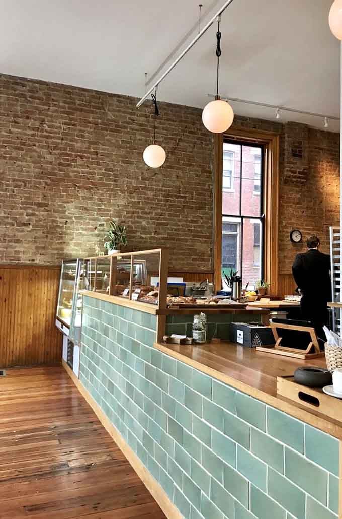 The mint-tiled counter and exposed brick walls create a charming backdrop for the serious business of coffee and pastry service.