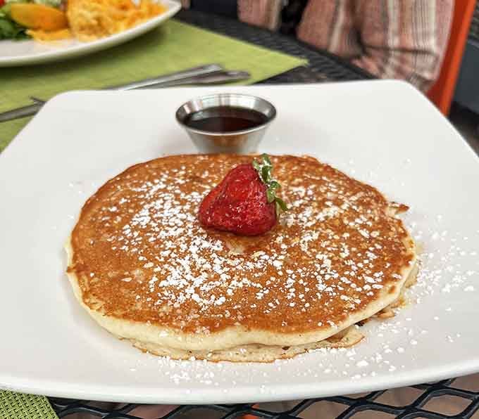 This isn't just a pancake, it's a fluffy, golden-brown canvas for butter and syrup, crowned with a strawberry like edible jewelry.