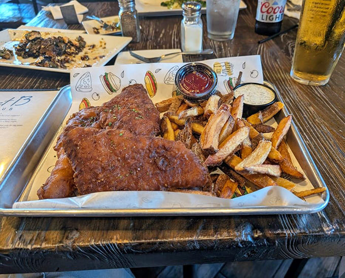 Beer-battered fish and chips arrive on a tray that looks like a delicious science experiment gone wonderfully right.