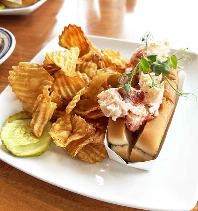 Lobster roll royalty served with chips that crunch and pickles that prove someone in the kitchen really cares.