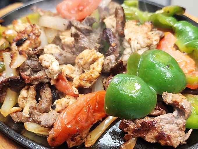 Sizzling fajitas announce their arrival with aromatic fanfare, loaded with perfectly grilled meat and colorful peppers that demand attention.