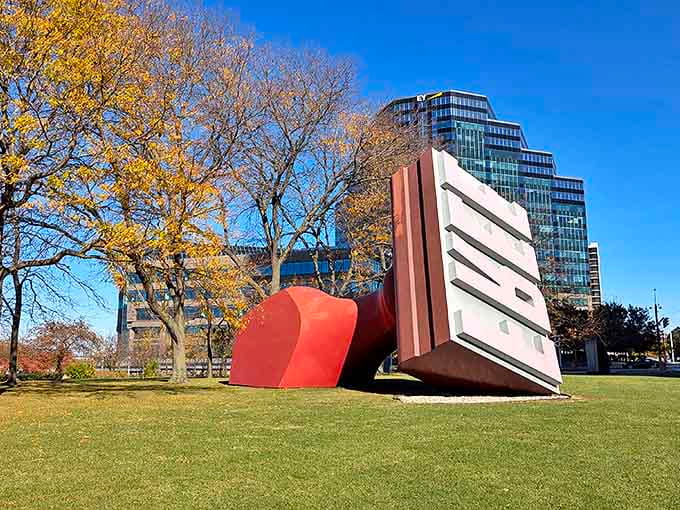 Autumn trees frame the Free Stamp against Cleveland's skyline, the sculpture's bold geometry playing against nature's organic forms.
