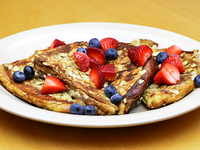 Nature's jewelry adorns this breakfast masterpiece – vibrant berries adding tart sweetness to buttery, golden perfection.