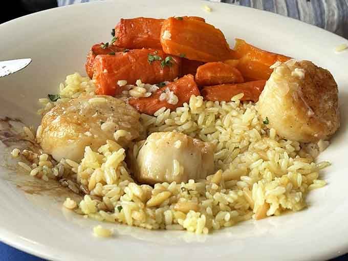 Sea scallops, fluffy rice, and glazed carrots create a plate that's as pleasing to the eye as it is to the palate, like edible art.