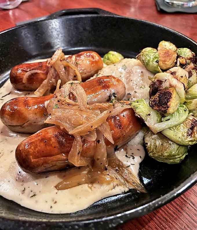 Plump, juicy bangers nestled on creamy mashed potatoes with caramelized onions and Brussels sprouts &ndash; comfort food that speaks with a delightful Irish accent.